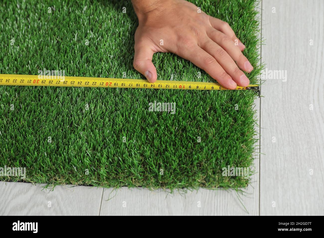 Man measuring artificial grass carpet indoors, above view Stock Photo ...