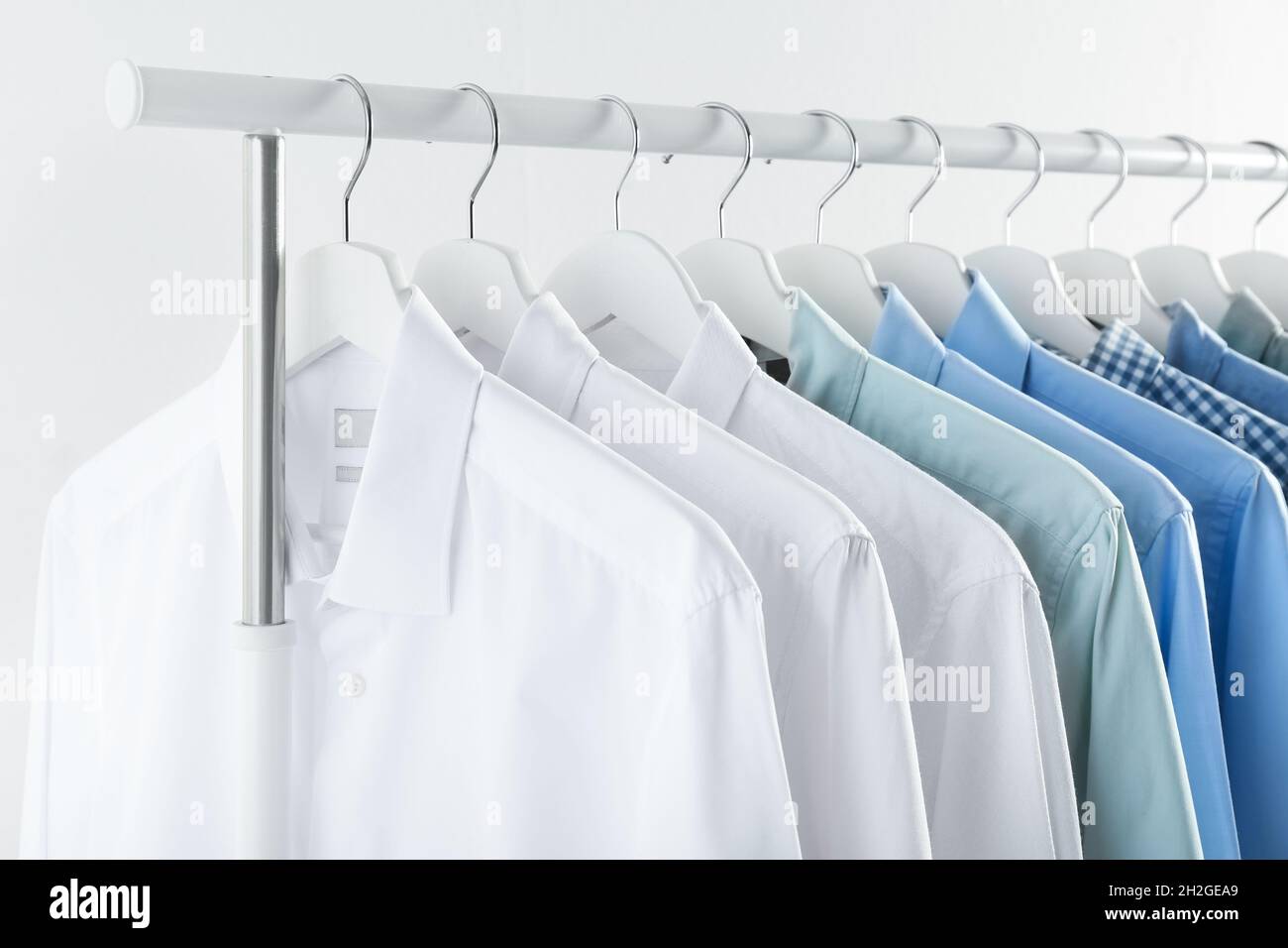 Men's clothes hanging on wardrobe rack against white background Stock ...