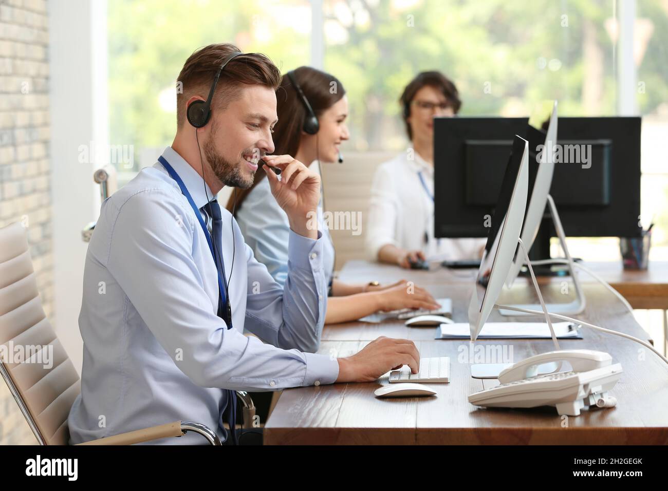 Technical support operators with headsets at workplace Stock Photo - Alamy