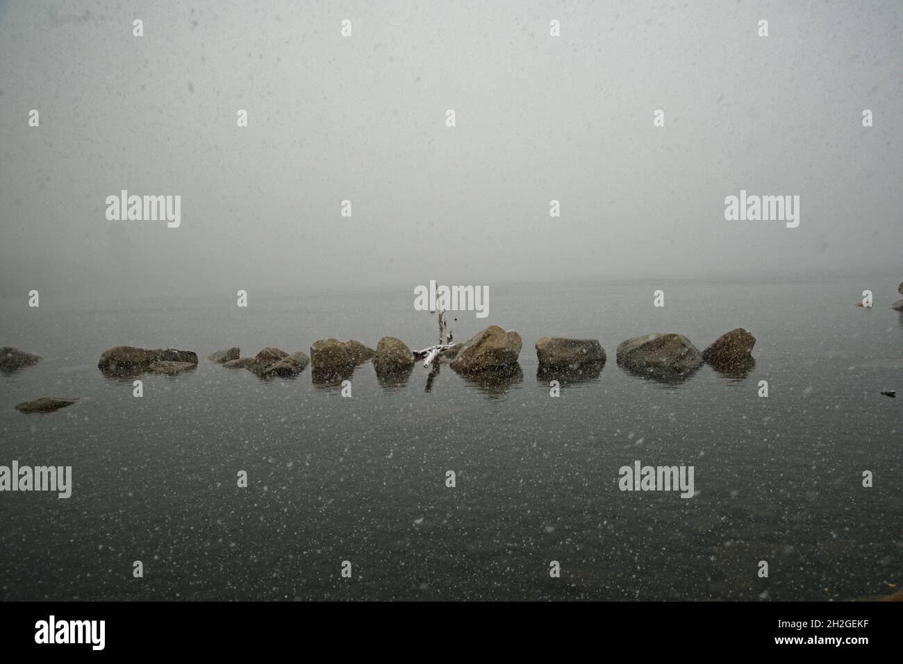 Fog & snow streaks at Convict Lake, with large rocks forming a line and ...