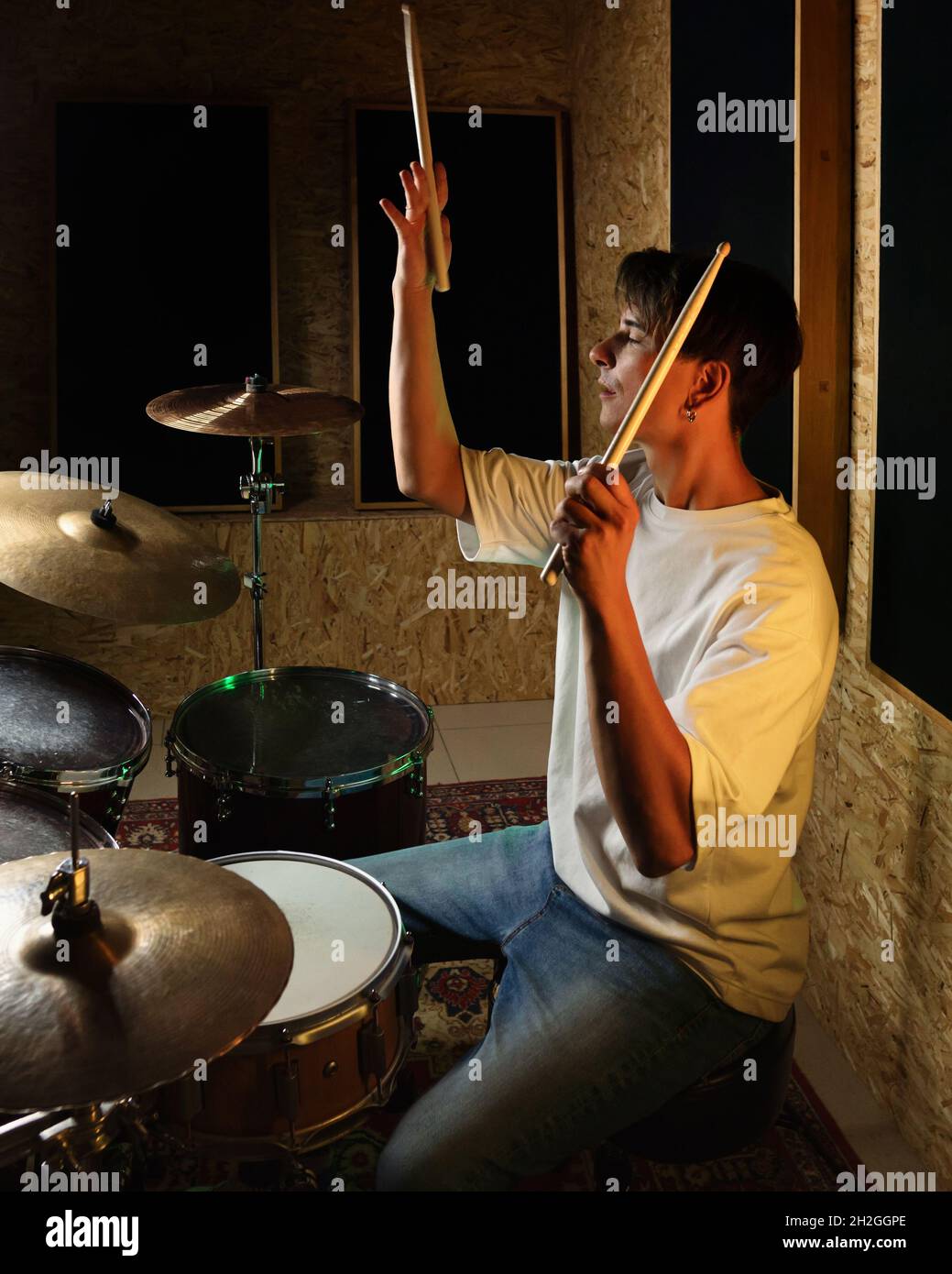 Drummer playing drums while sitting at drum kit with colorful backlit ...