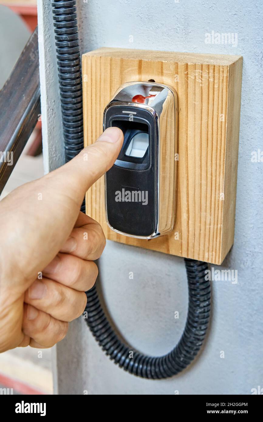 Worker uses contemporary biometric fingerprint scanner to record shift ...