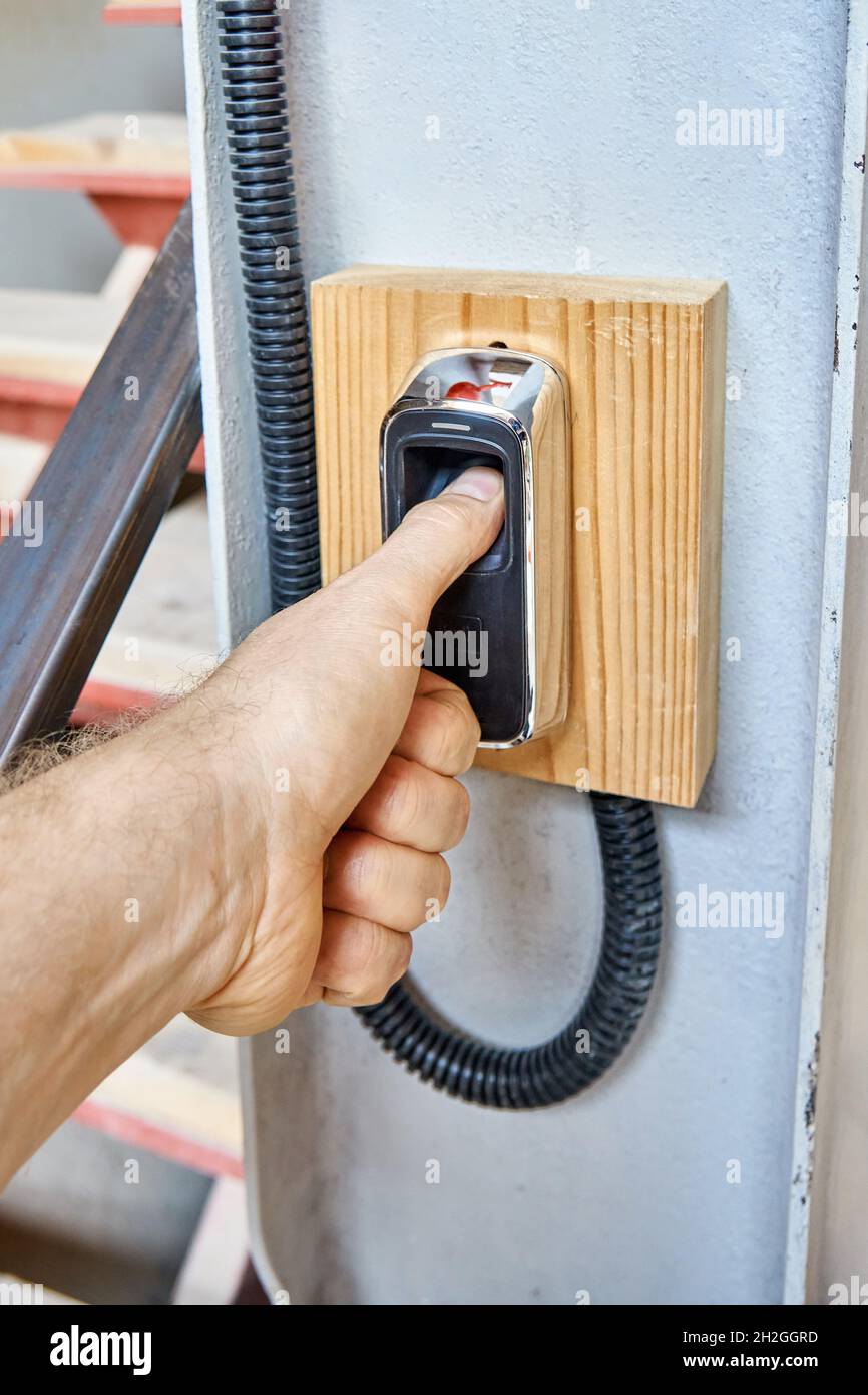 Worker uses contemporary biometric fingerprint scanner to record shift ...