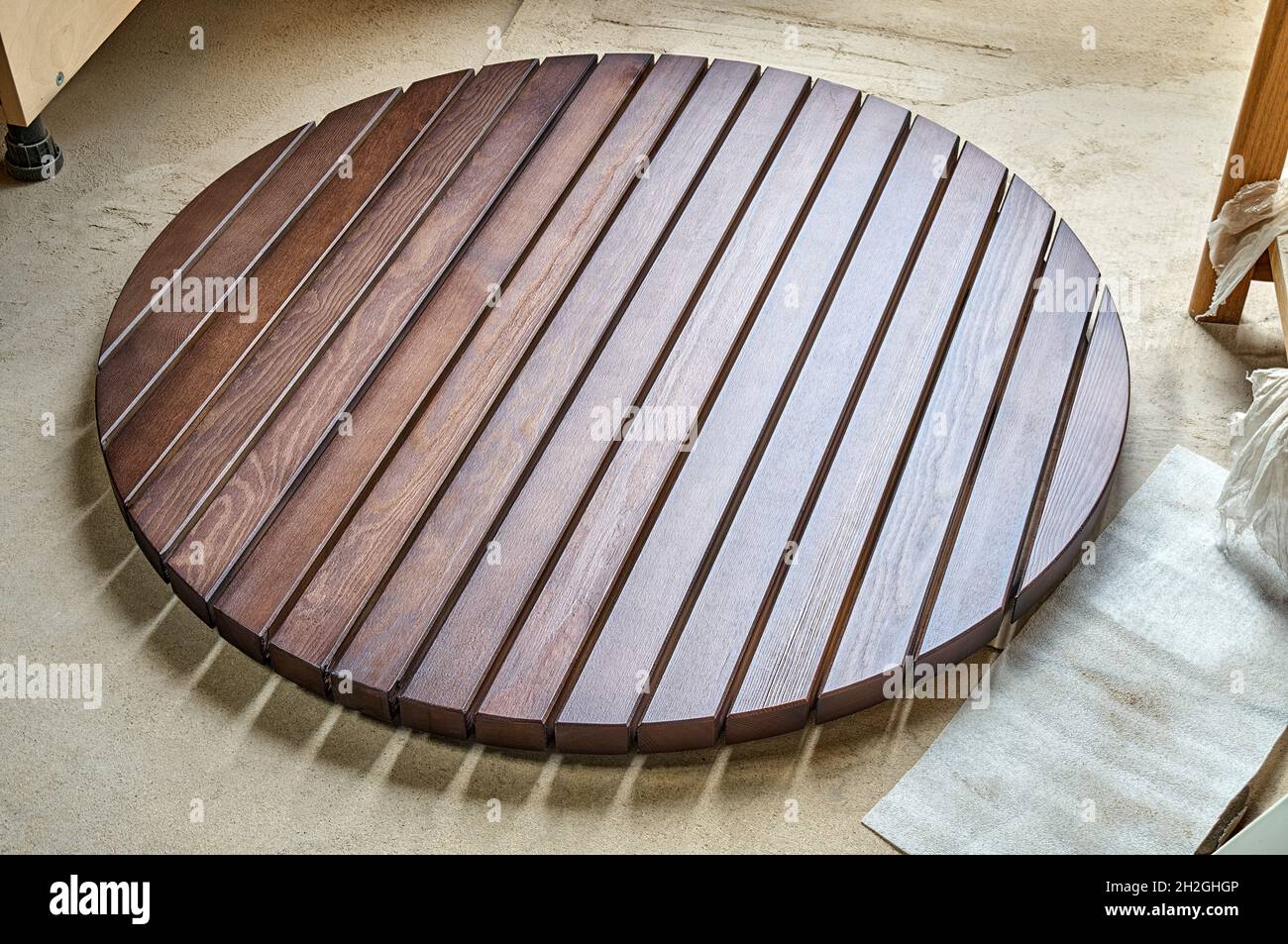 Round table top made of wooden slats for outdoor table lying on dusty ...