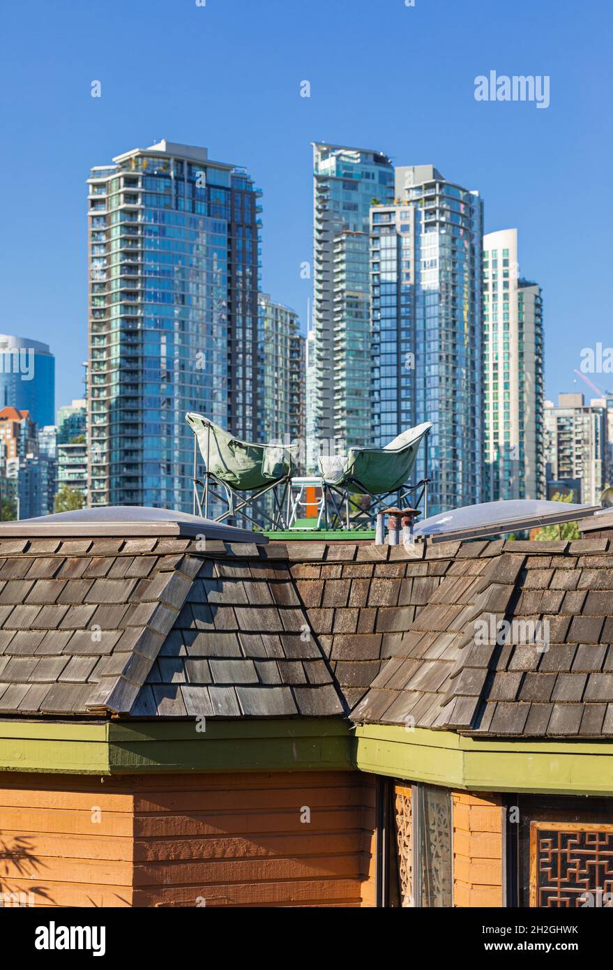 Folding chairs for relax on the roof top of a house with cityscape on ...