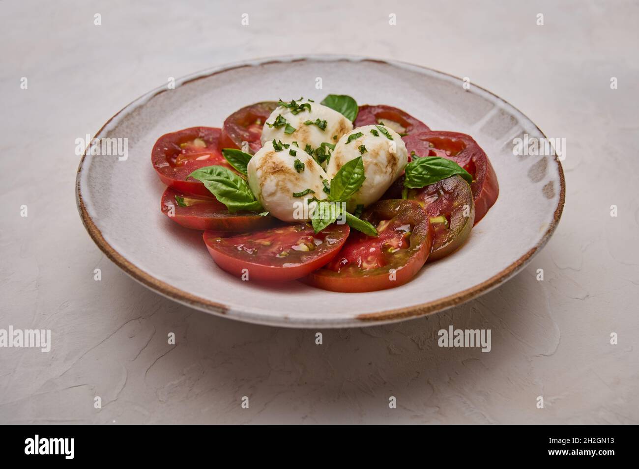 Delicious caprese salad in ceramic light plate. Close up Stock Photo ...