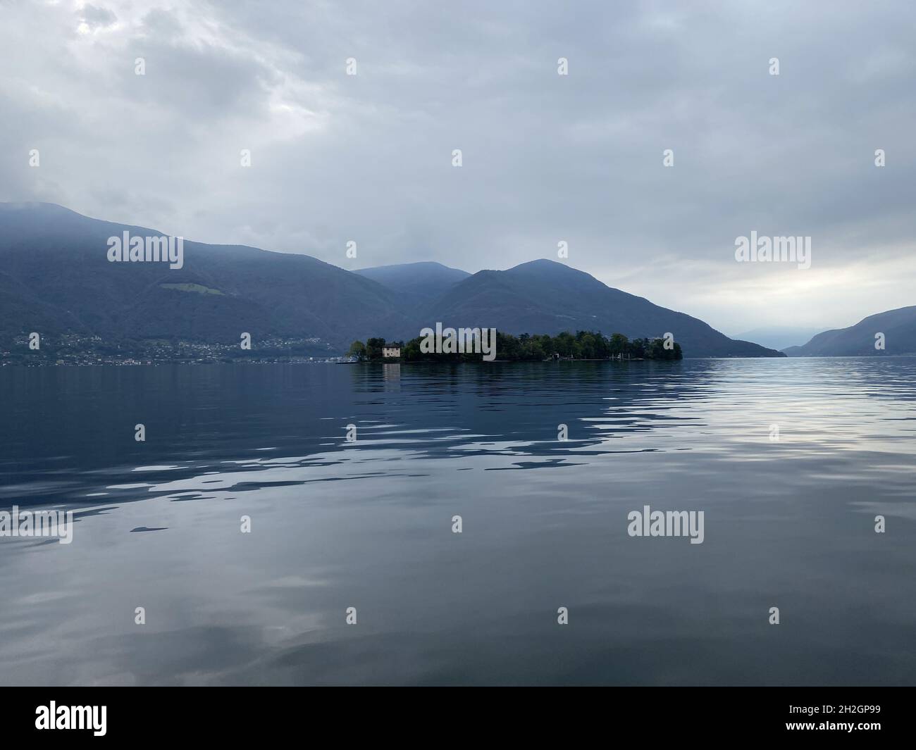 Beautiful clean lake surrounded by mountains under a gray cloudy sky on ...