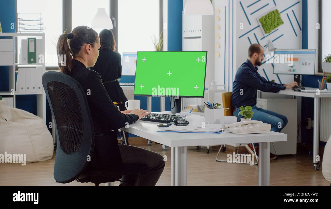 Corporate employee using computer with horizontal green screen for ...