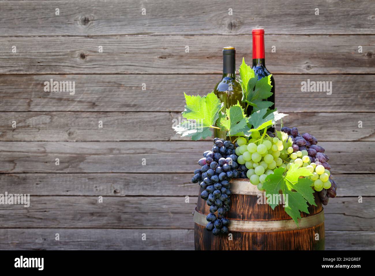 Various colorful grapes and wine bottles on wine barrel on outdoor ...