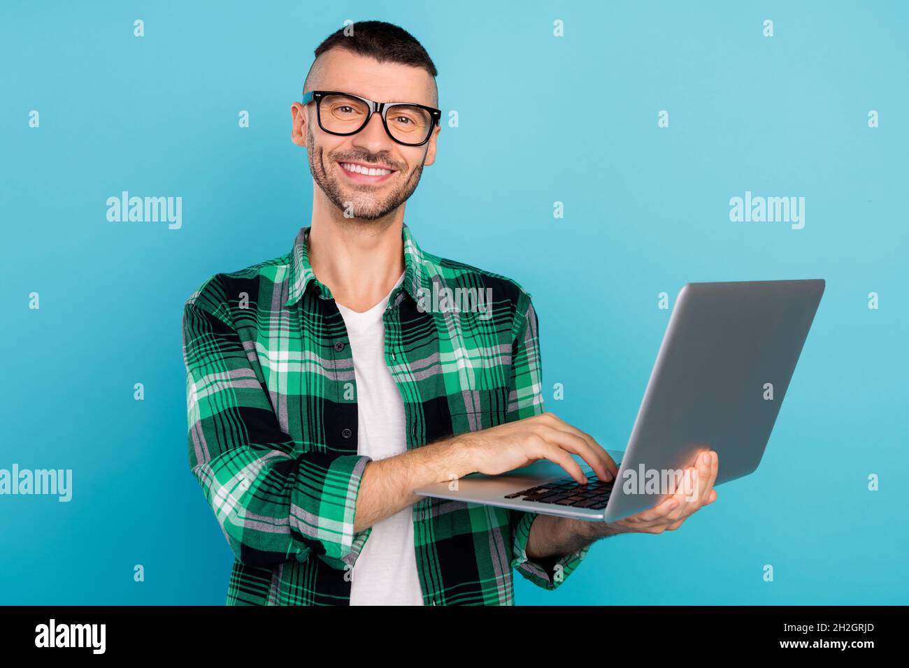 Photo of happy young positive man look hold hand laptop good mood smile ...