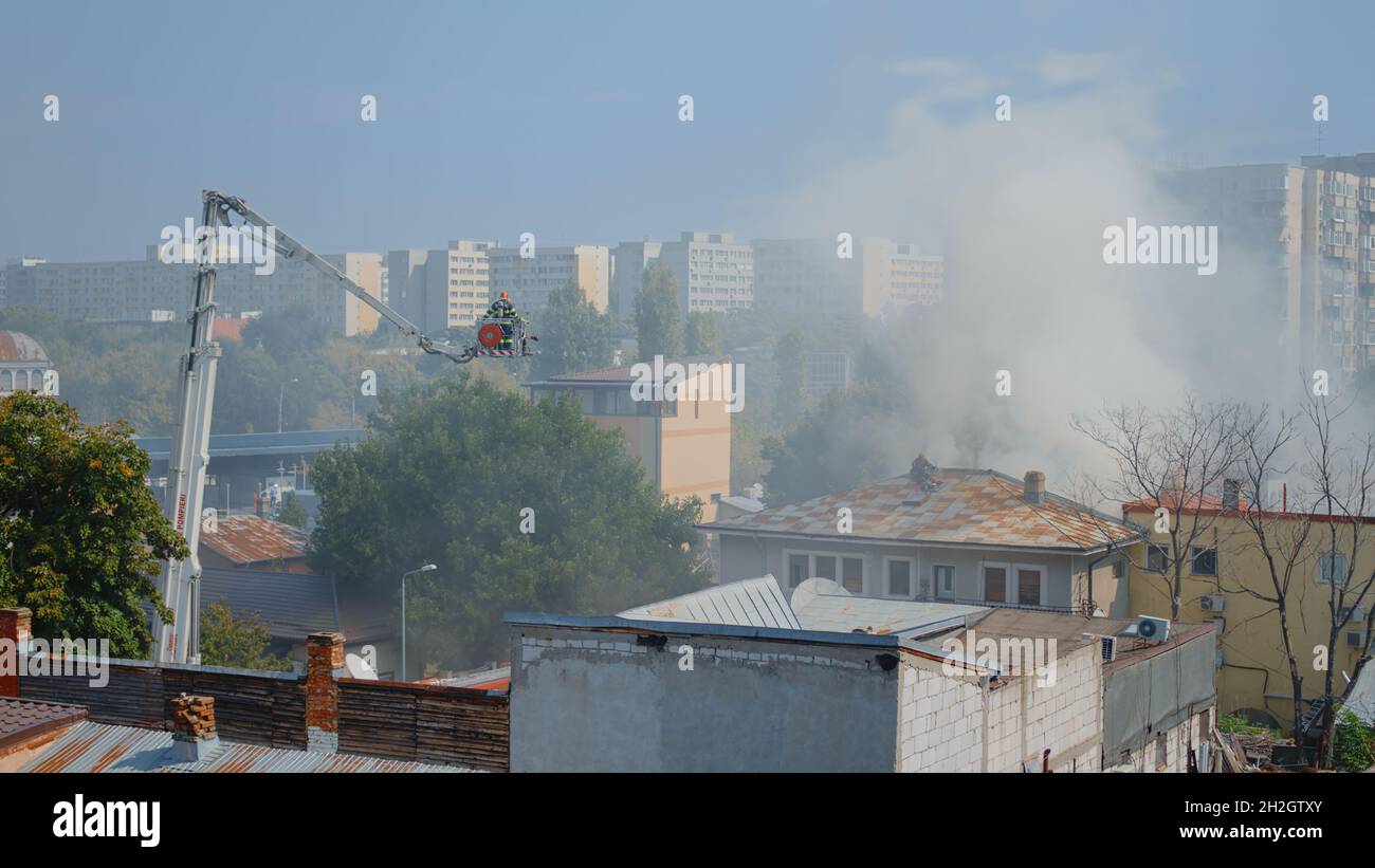 Firefighters on platform truck waiting to go on house roof to stop fire ...