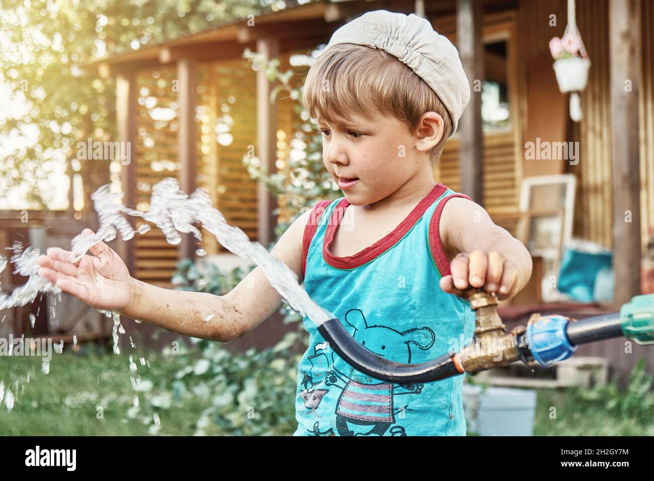 Blond little kid boy turns lever on tap with rubber hose and running up ...