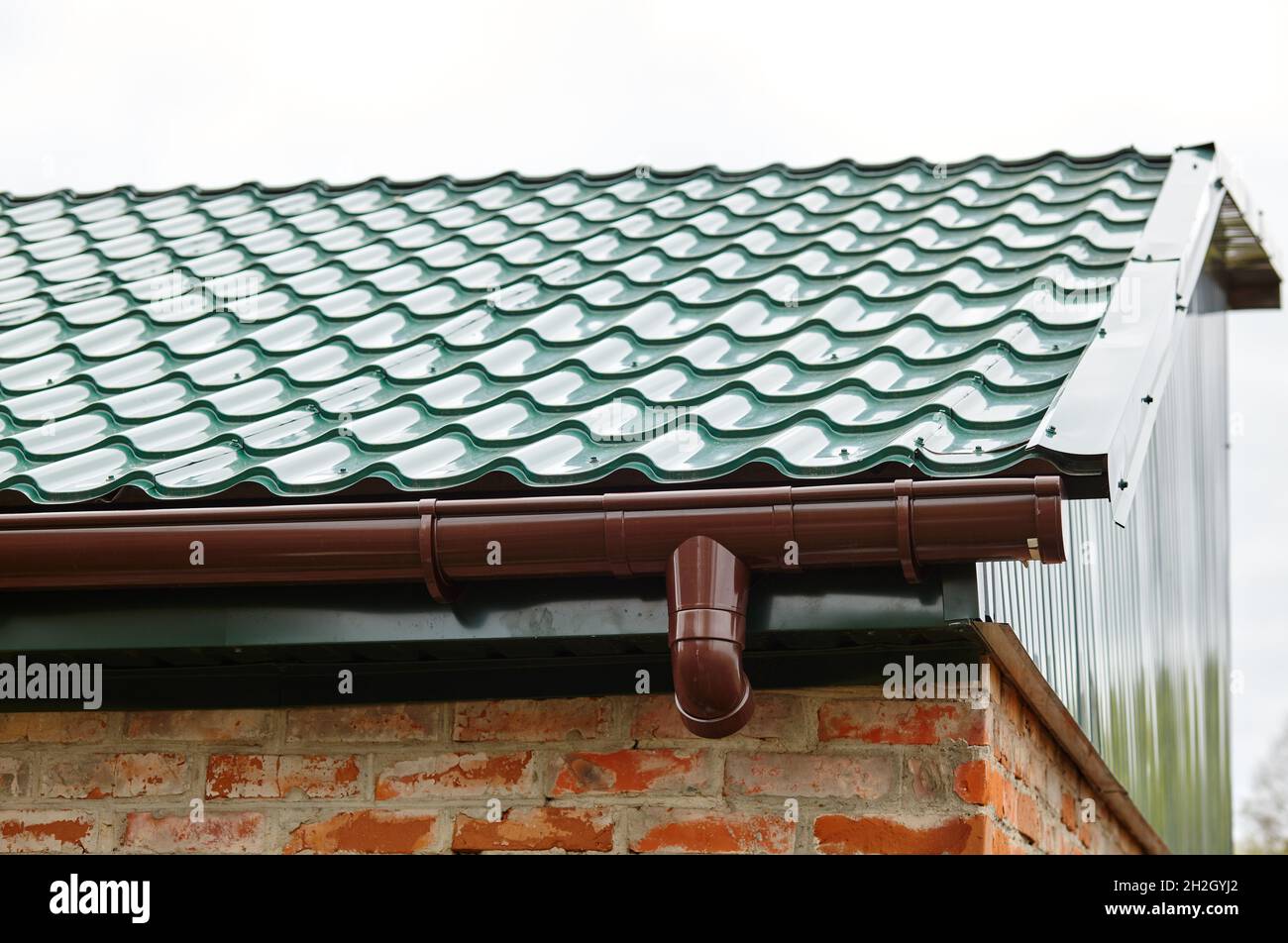 Facade of a suburban building with downspout. View of the roof against ...