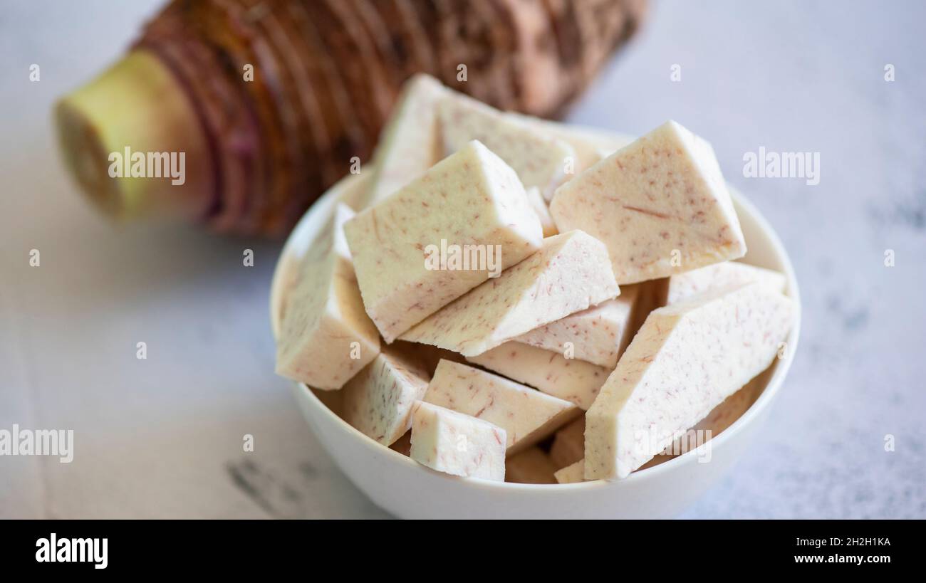 Taro root with slice cubes on bowl and dark background, Fresh raw ...