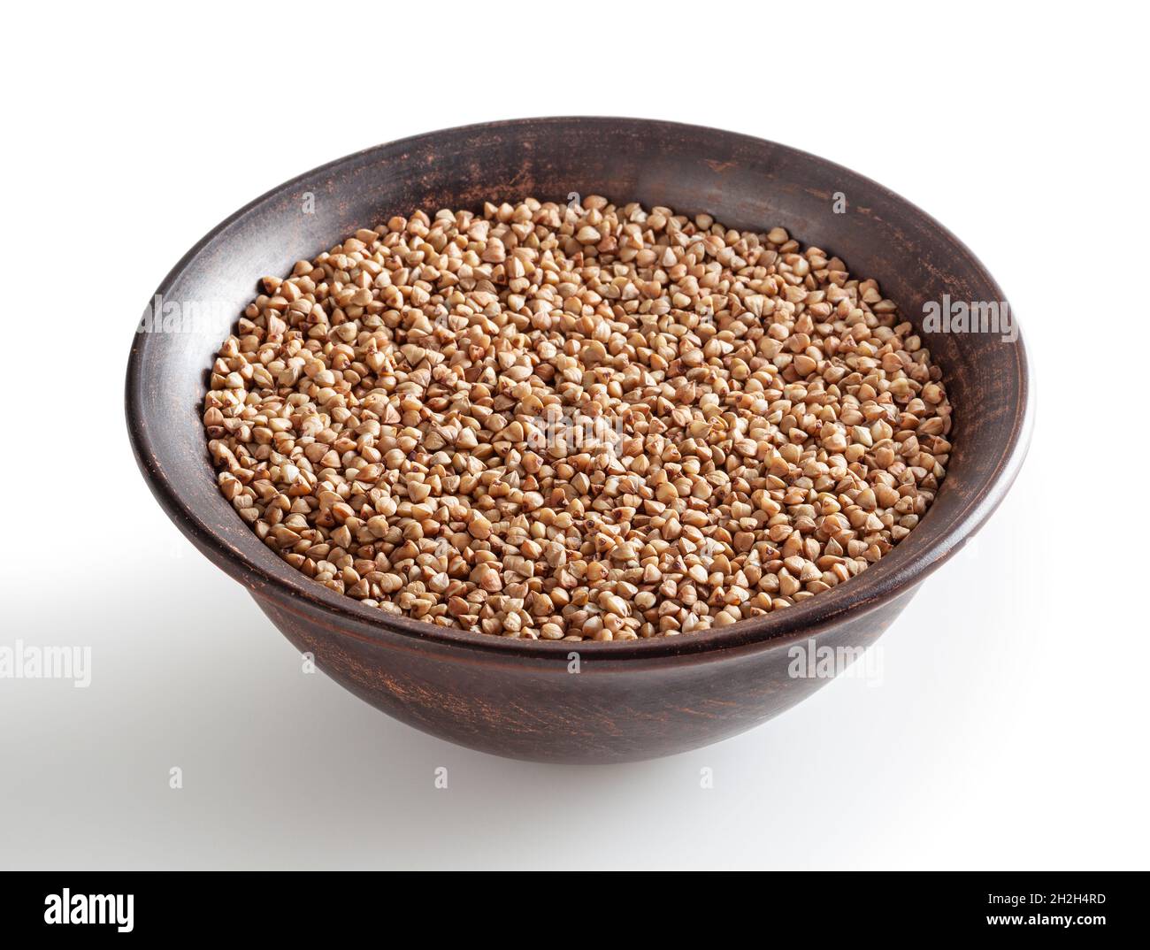 Uncooked roasted buckwheat in ceramic bowl isolated on white background ...