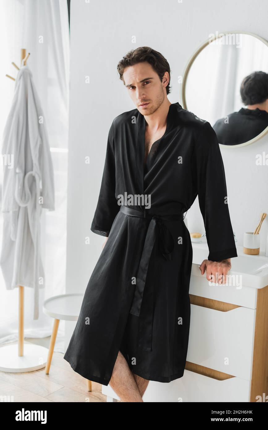 Young man in satin robe standing near sink in bathroom Stock Photo - Alamy