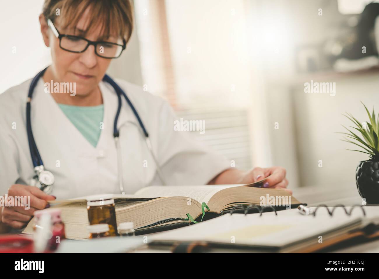 Female doctor reading a textbook in medical office Stock Photo - Alamy