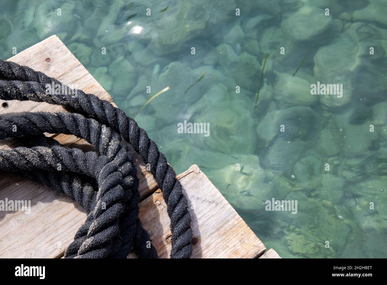 Rolled up black ropes on a boating dock yard in Spain Stock Photo - Alamy
