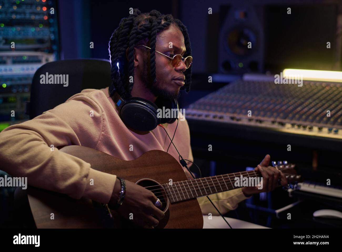 African young musician playing guitar and writing a song while sitting ...