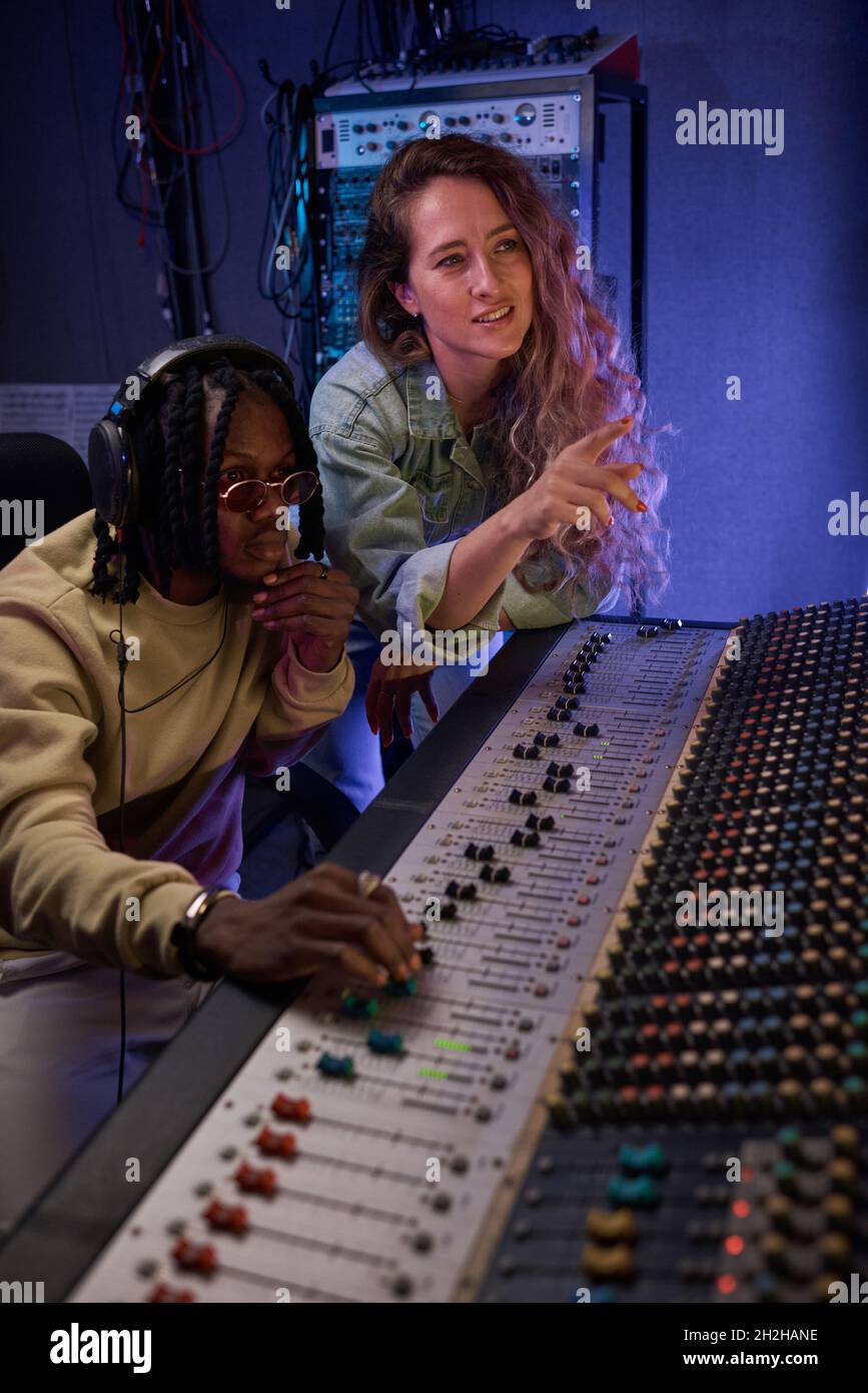 Young couple using musical keyboard to record a song in the recording ...