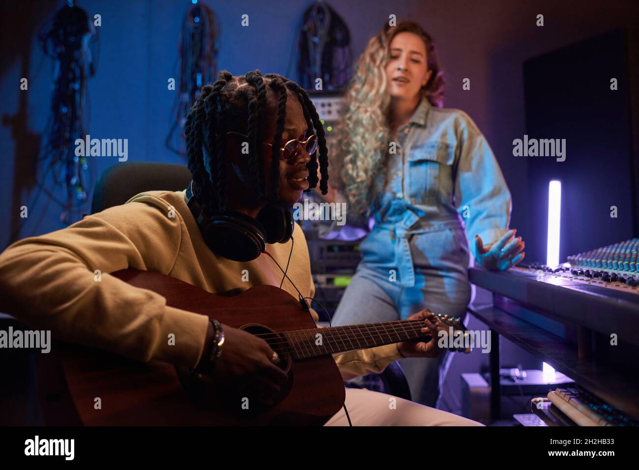 African young musician playing guitar while young woman singer in the ...