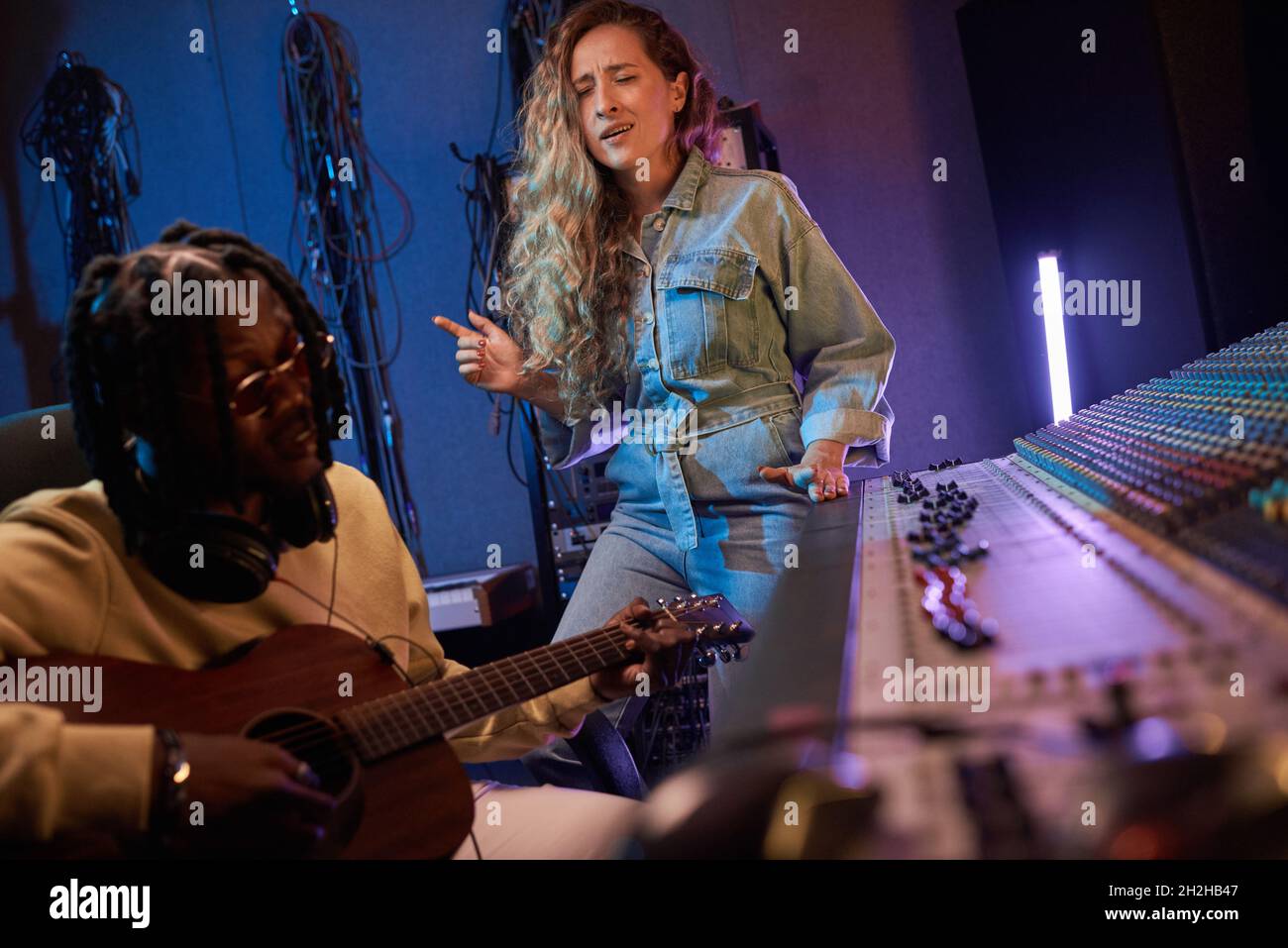 Young pretty singer singing while man playing guitar they recording a ...