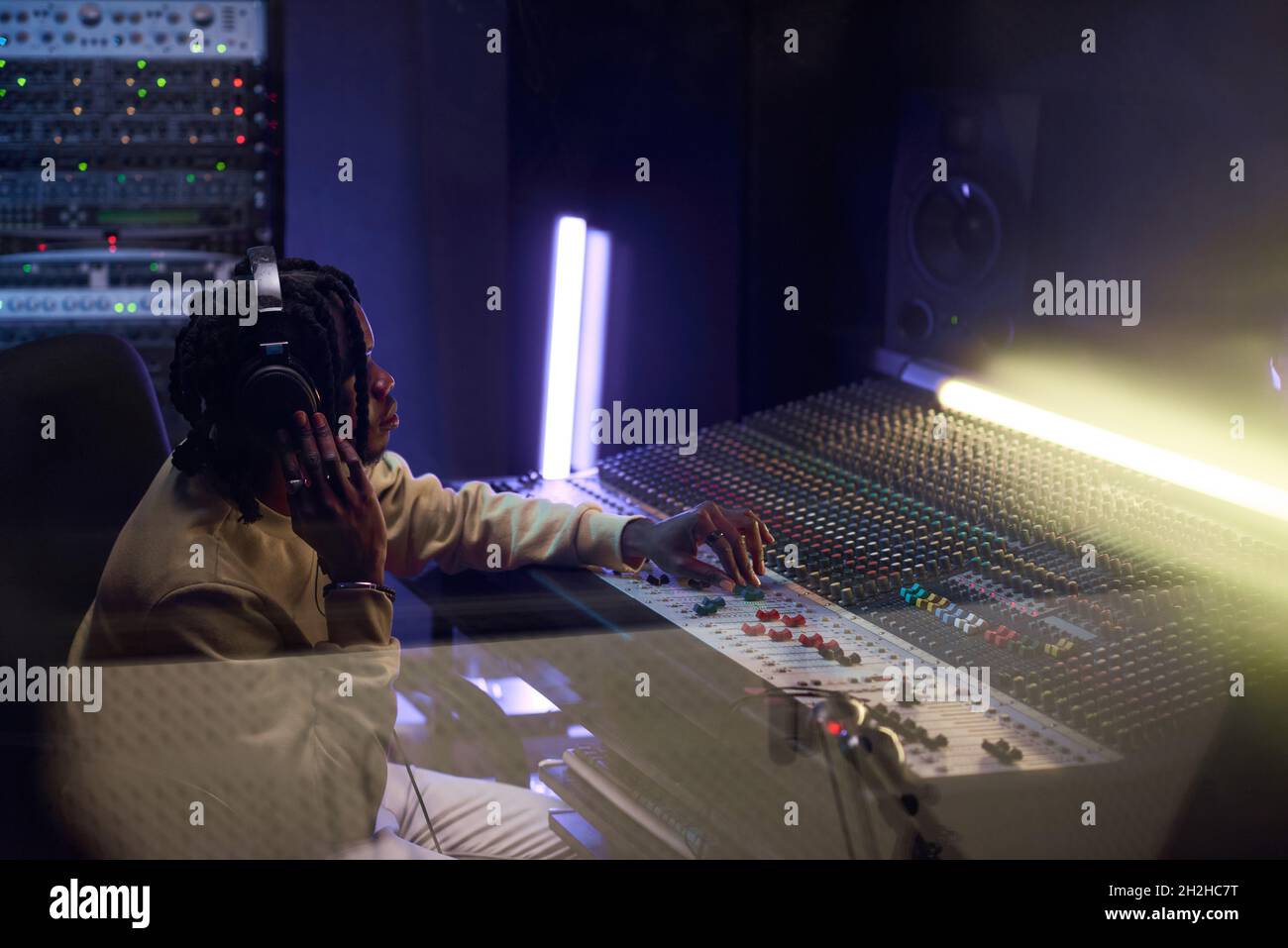 African composer in headphones using music keyboard to write new song ...