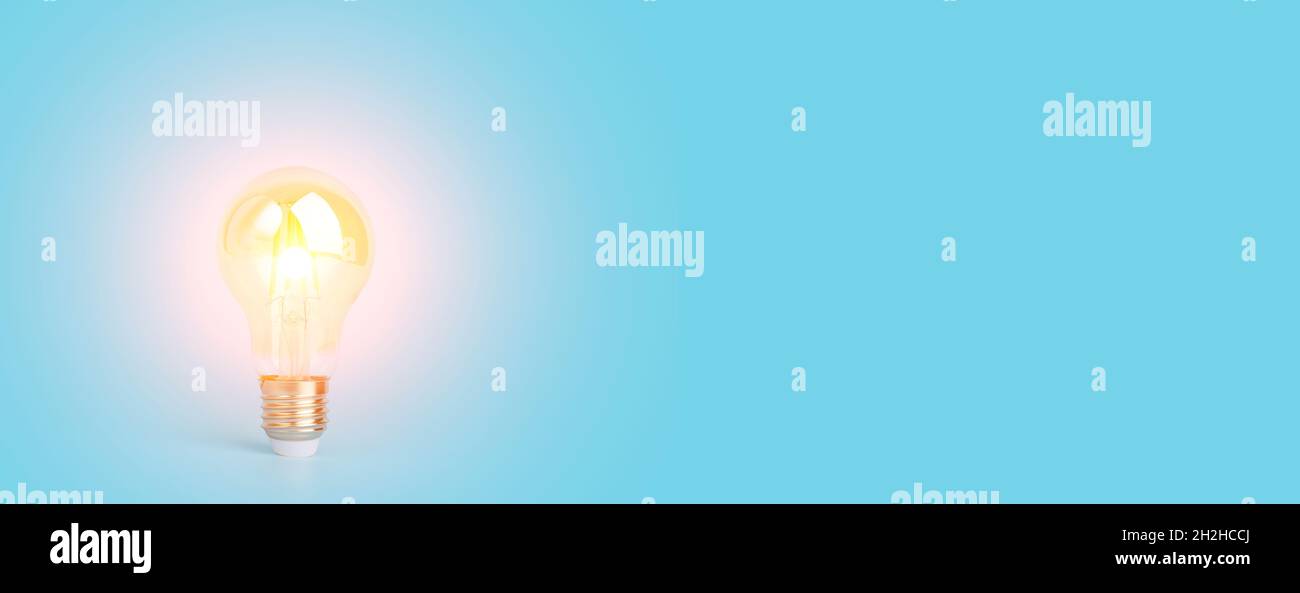 Knowledge and idea concept. Light bulb with light on a blank blue ...