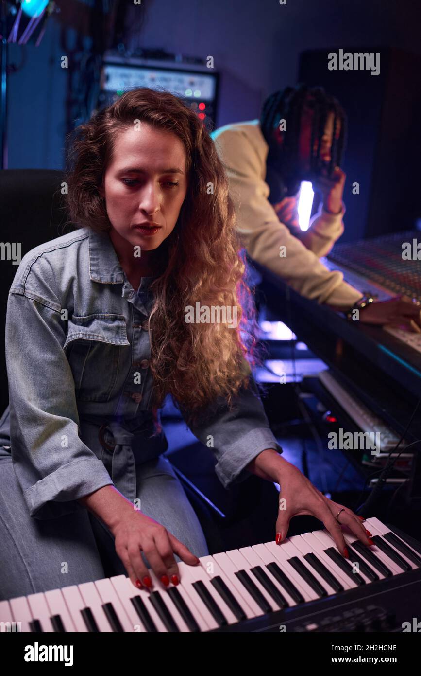 Young female musician playing synthesizer in the recording studio with ...