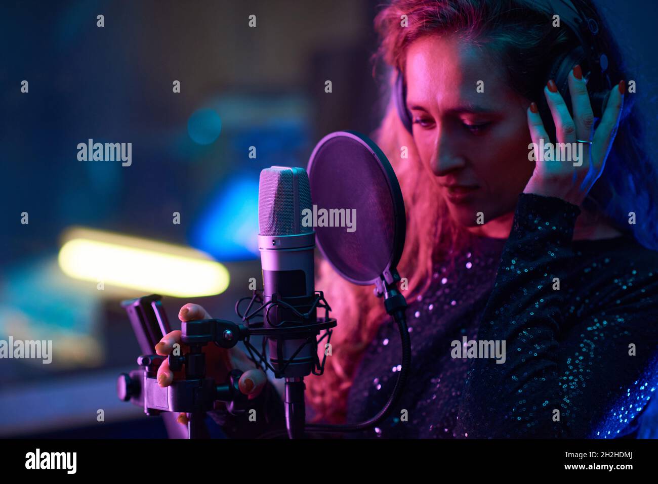 Beautiful singer in headphones writing a new song in the recording ...