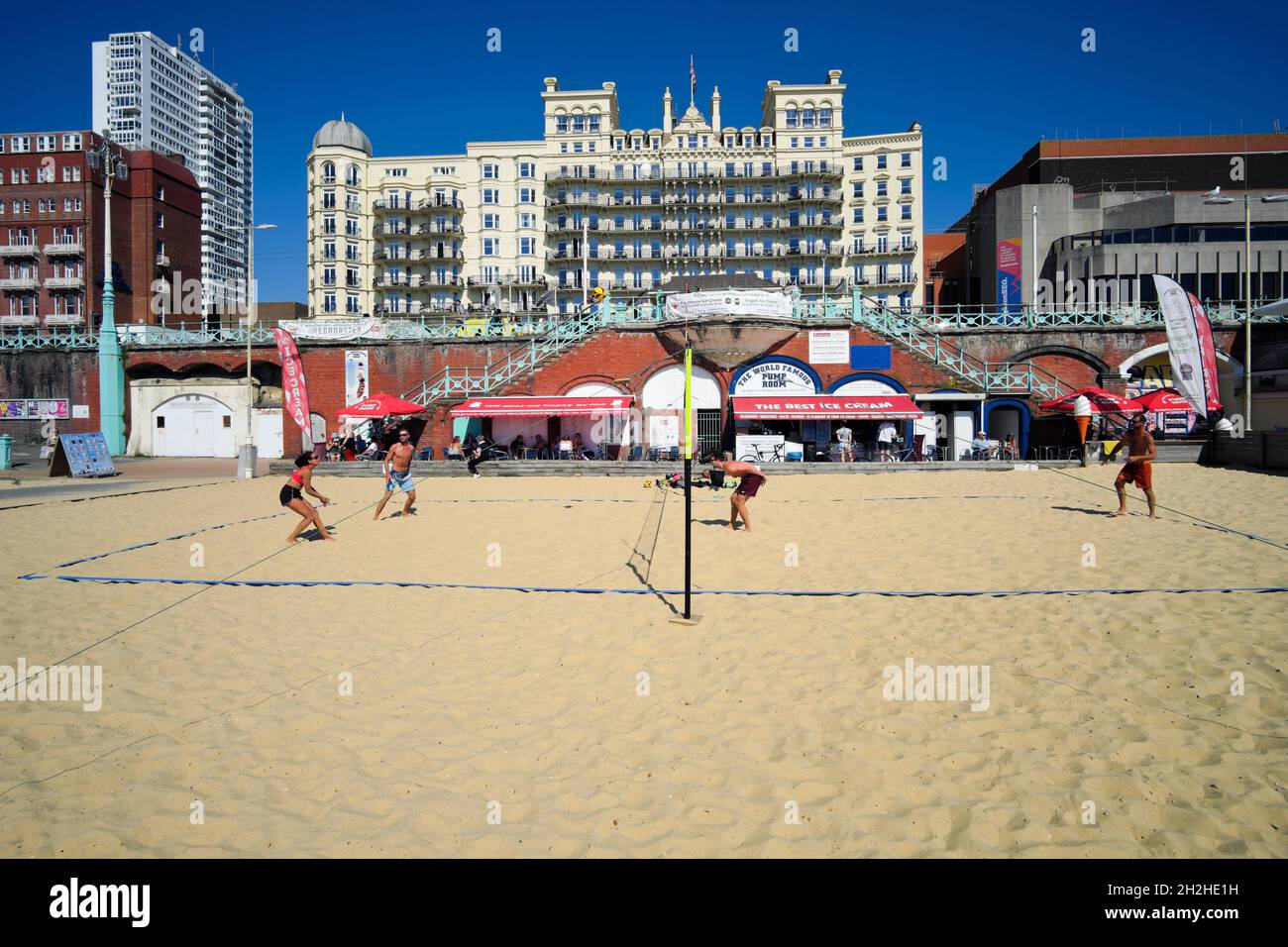Four young people playing volleyball on Brighton beach in front of the ...