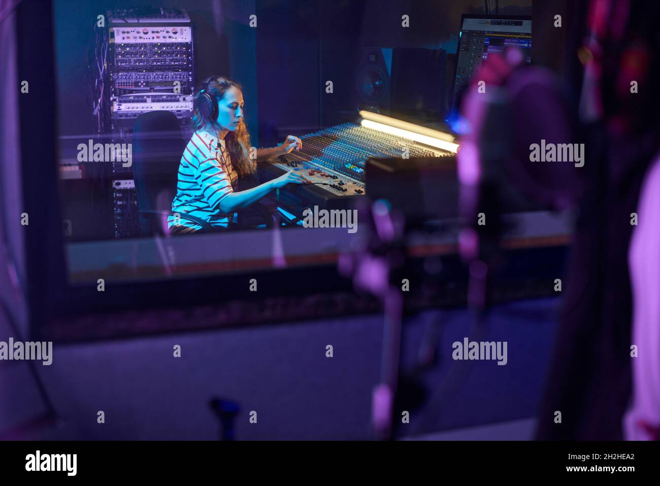 Young musical producer using music keyboard to record a song for singer ...