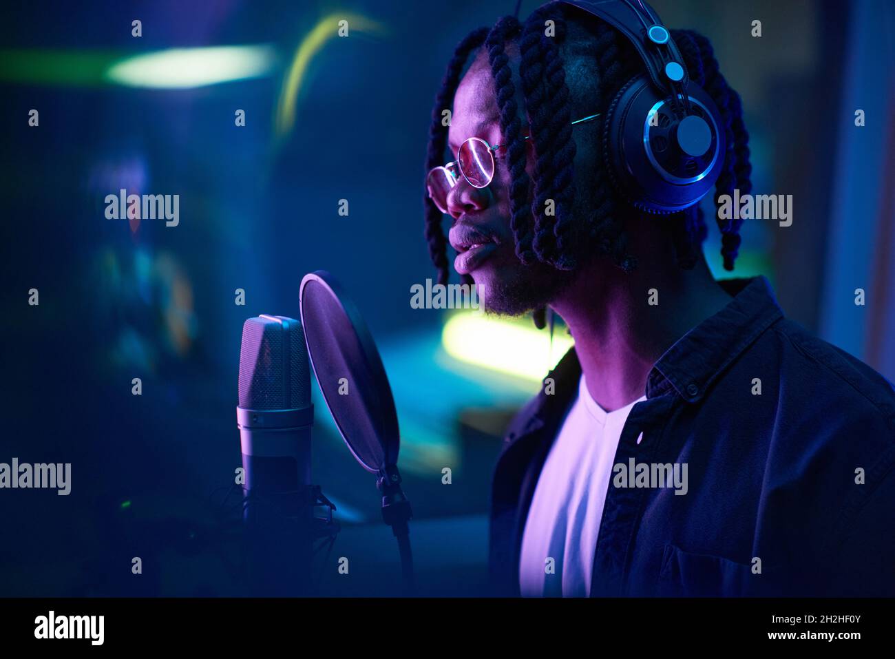 African singer with dreadlocks singing to microphone and recording a ...