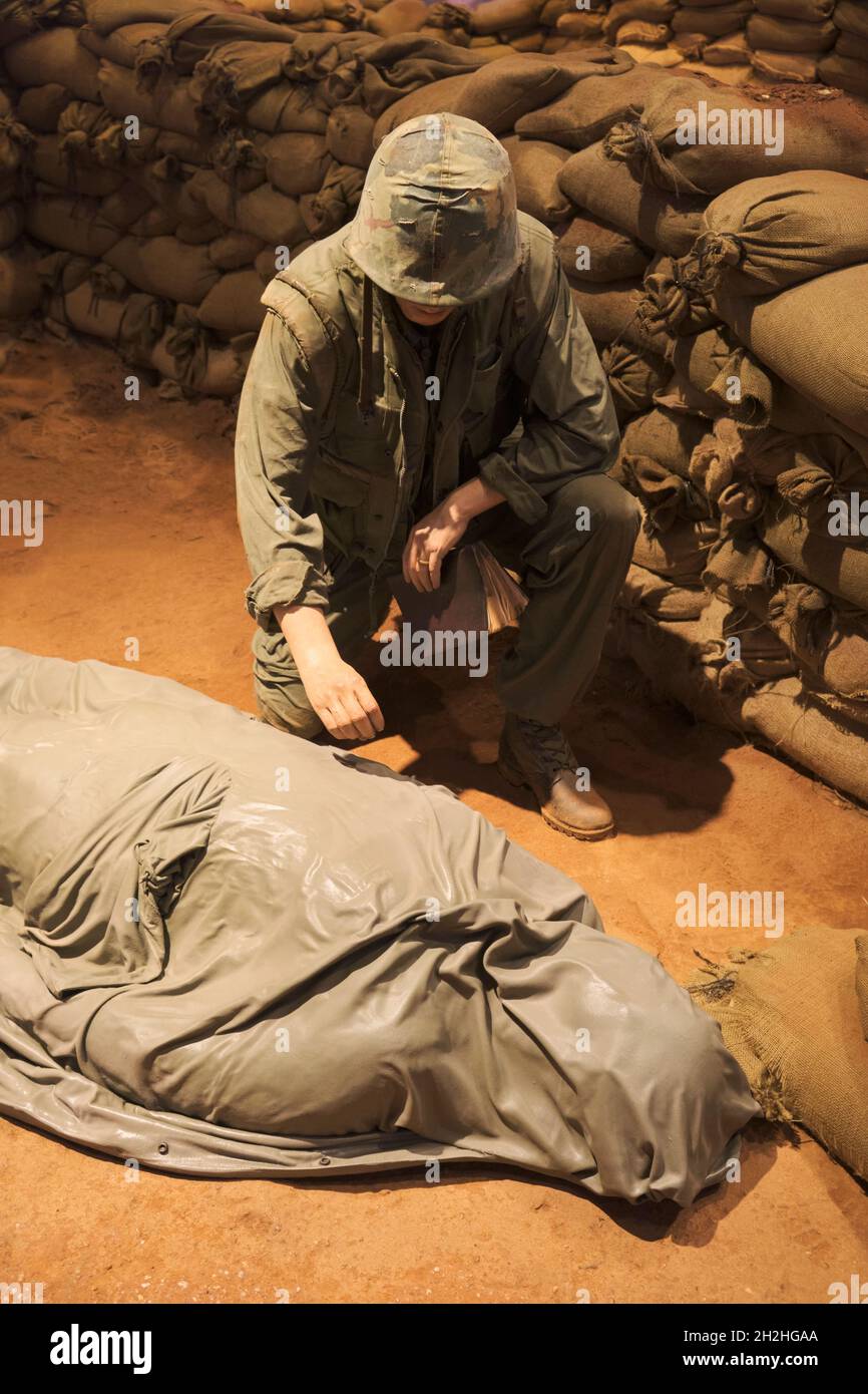 A chaplain, priest with a bible delivers a prayer to a dead soldier in ...