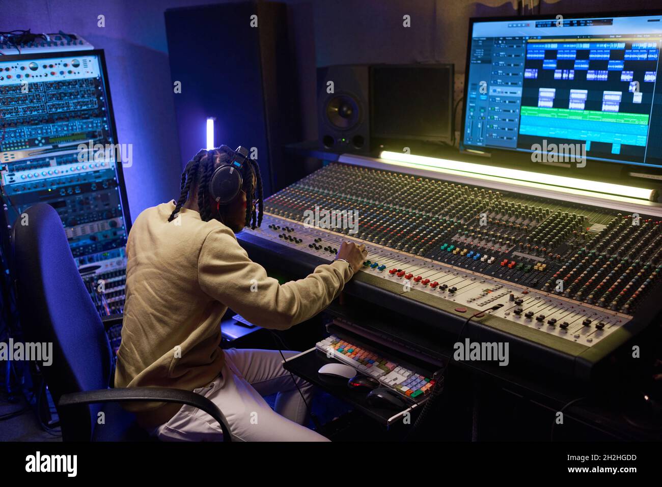 African musical producer in headphones working on sound mixing board in ...