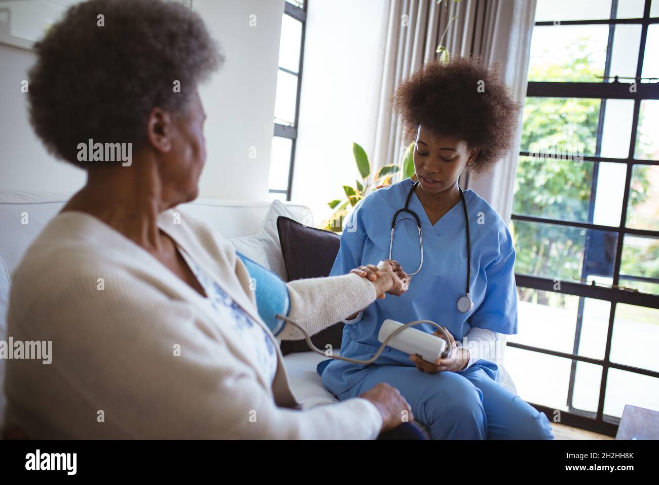 African american female doctor treating senior female patient at home ...