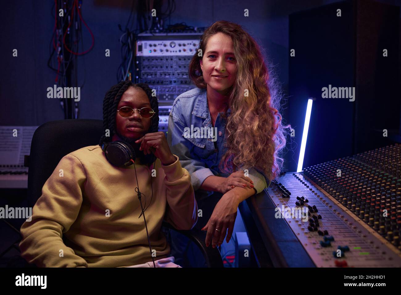 Portrait of young singer with her musical producer looking at camera ...
