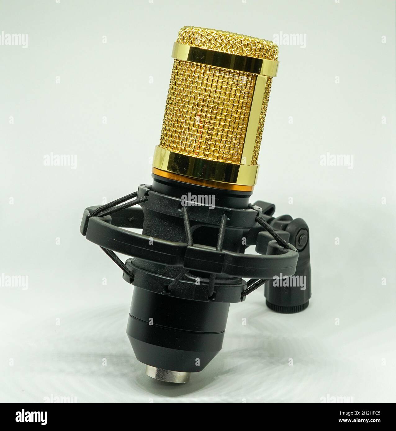 Vertical shot of a gold-plated microphone isolated on white background ...