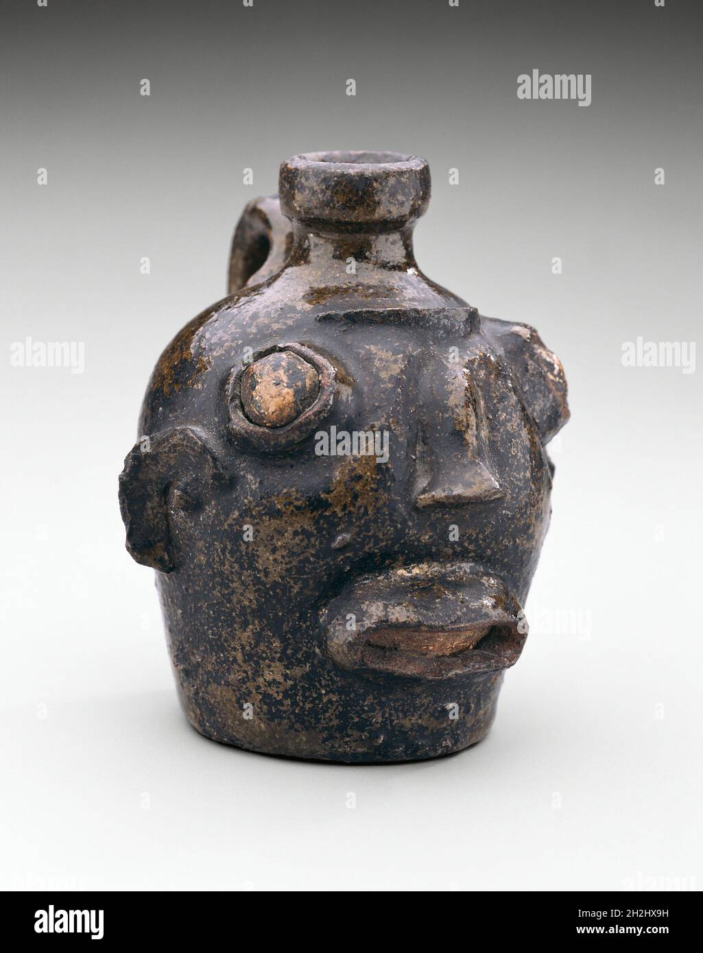 Face Jug, c. 1860. Small, dark colored ceramic vessel with a handle and ...