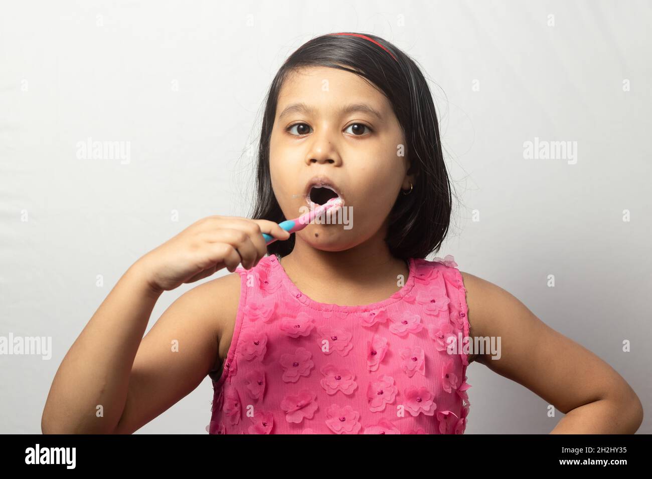 Portrait of an Indian girl child brushing teeth with toothbrush on ...