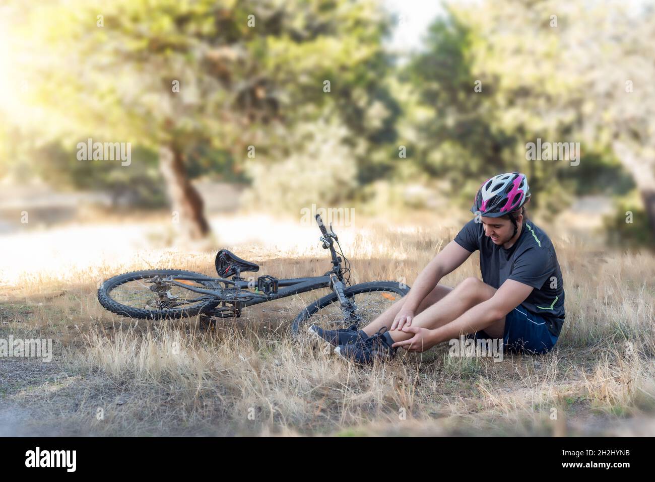 Male cyclist in an accident in the countryside. A young cyclist lying ...