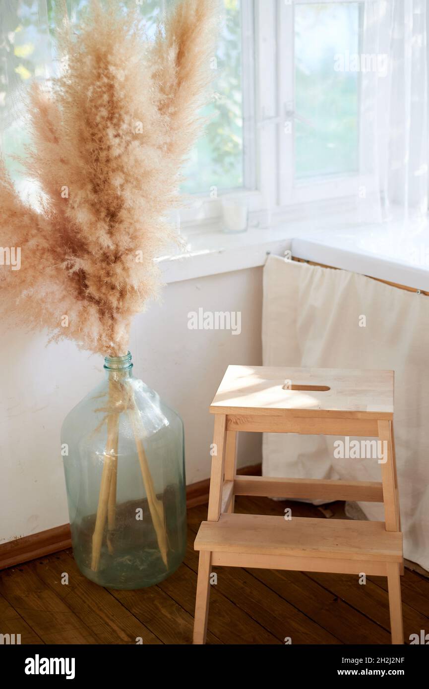 A huge bottle with pampas, a ladder in the bathroom with a large bright ...