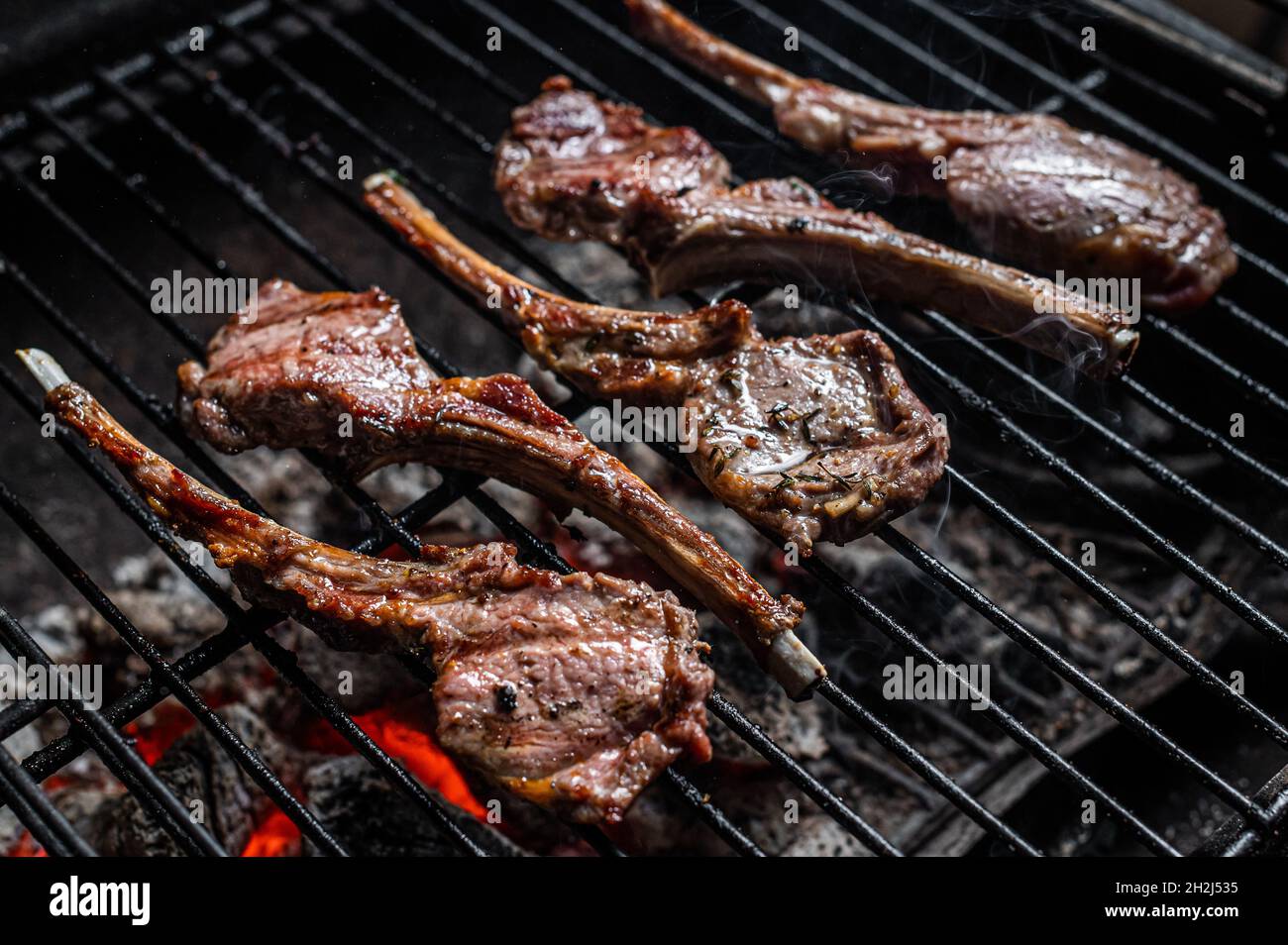 Grilled lamb mutton chop steaks on barbecue, outdoor BBQ grill with ...