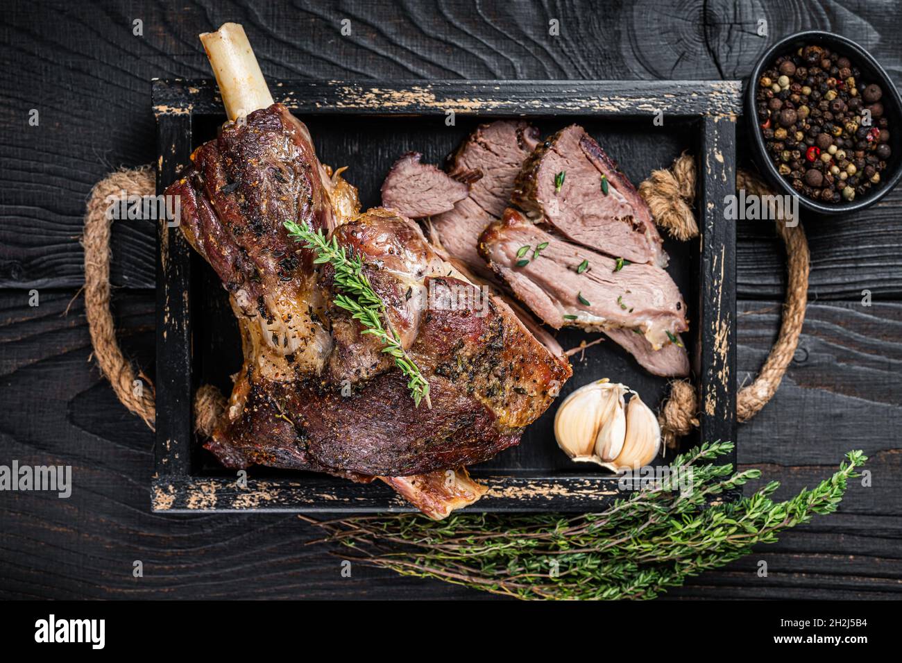 Roasted mutton lamb leg sliced in a wooden tray with meat cleaver ...