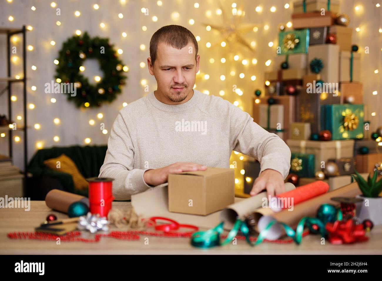 Handsome happy man wrapping christmas gifts at home Stock Photo - Alamy