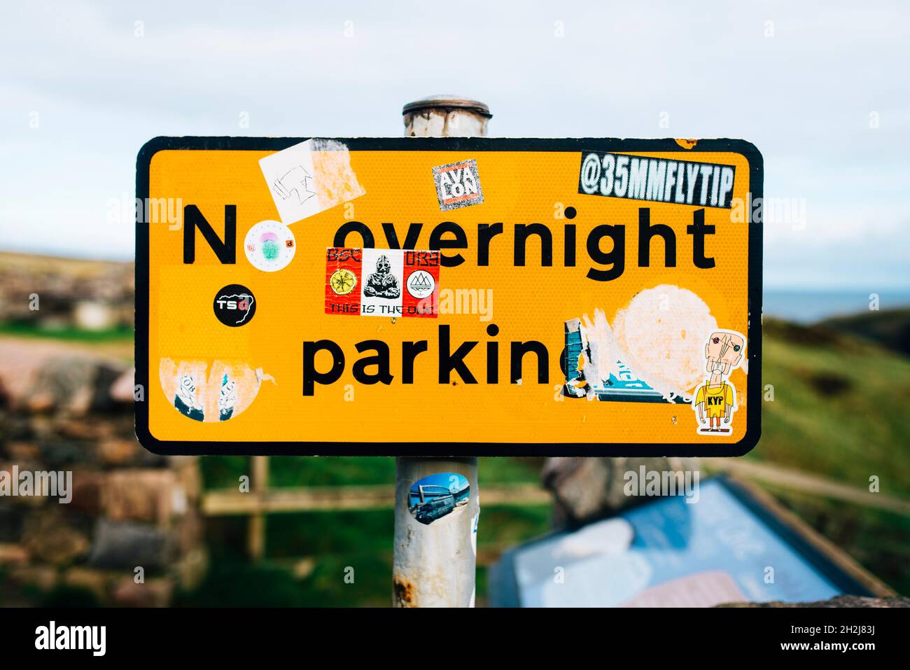 A no overnight parking sign defaced by stickers Stock Photo - Alamy