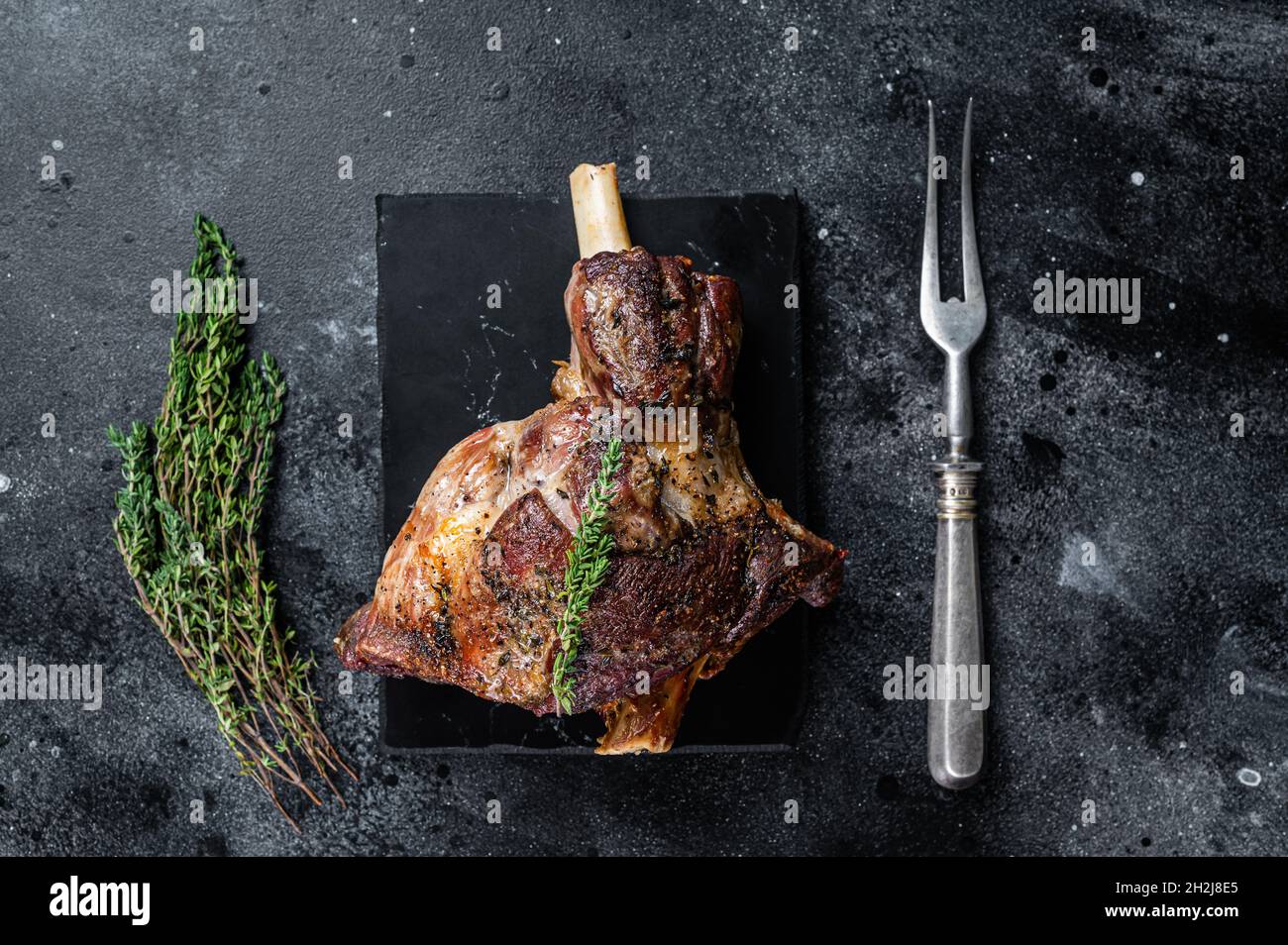 Oven Roasted lamb mutton whole leg with thyme. Black background. Top ...