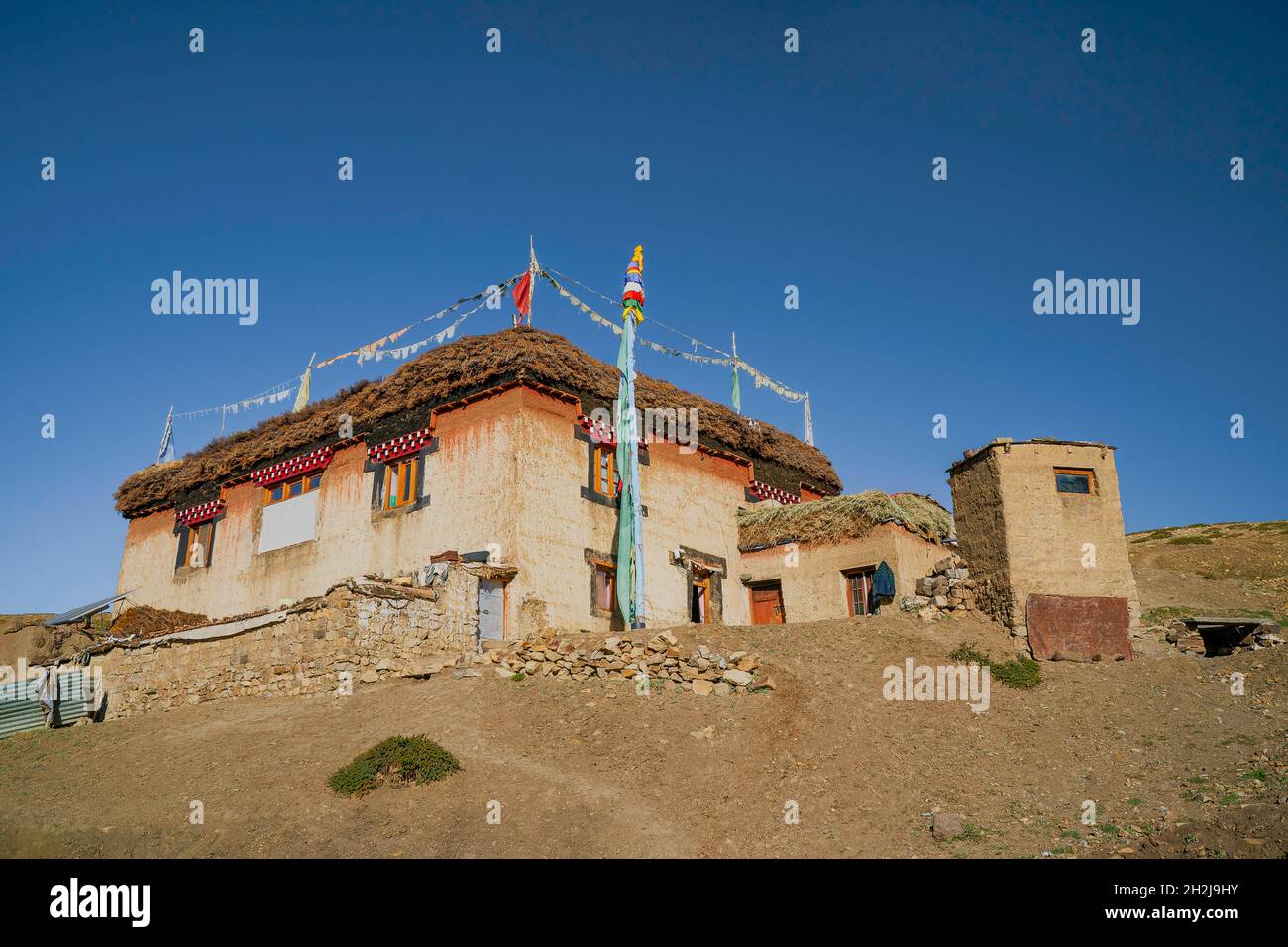 A traditional house with animal fodder drying on rooftop and Buddhist ...