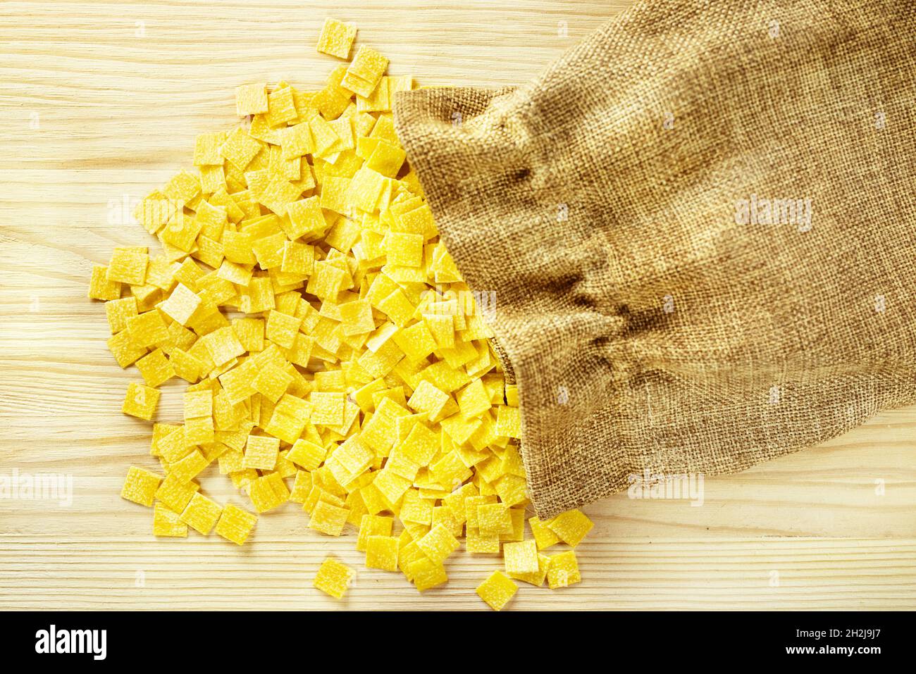 Pile of small flat squares of egg pasta called quadrucci sackcloth bag ...