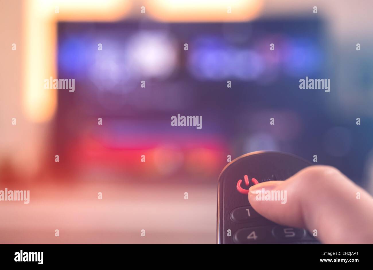 Hand with TV remote control turn off the television by pressing on red ...